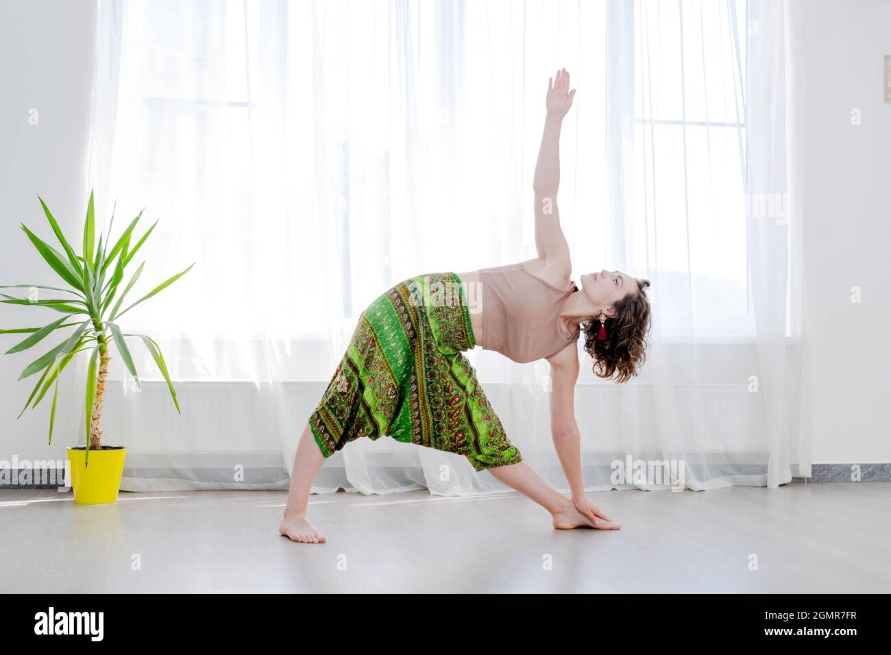 Young woman practicing yoga, standing in Utthita Trikonasana exercise ...