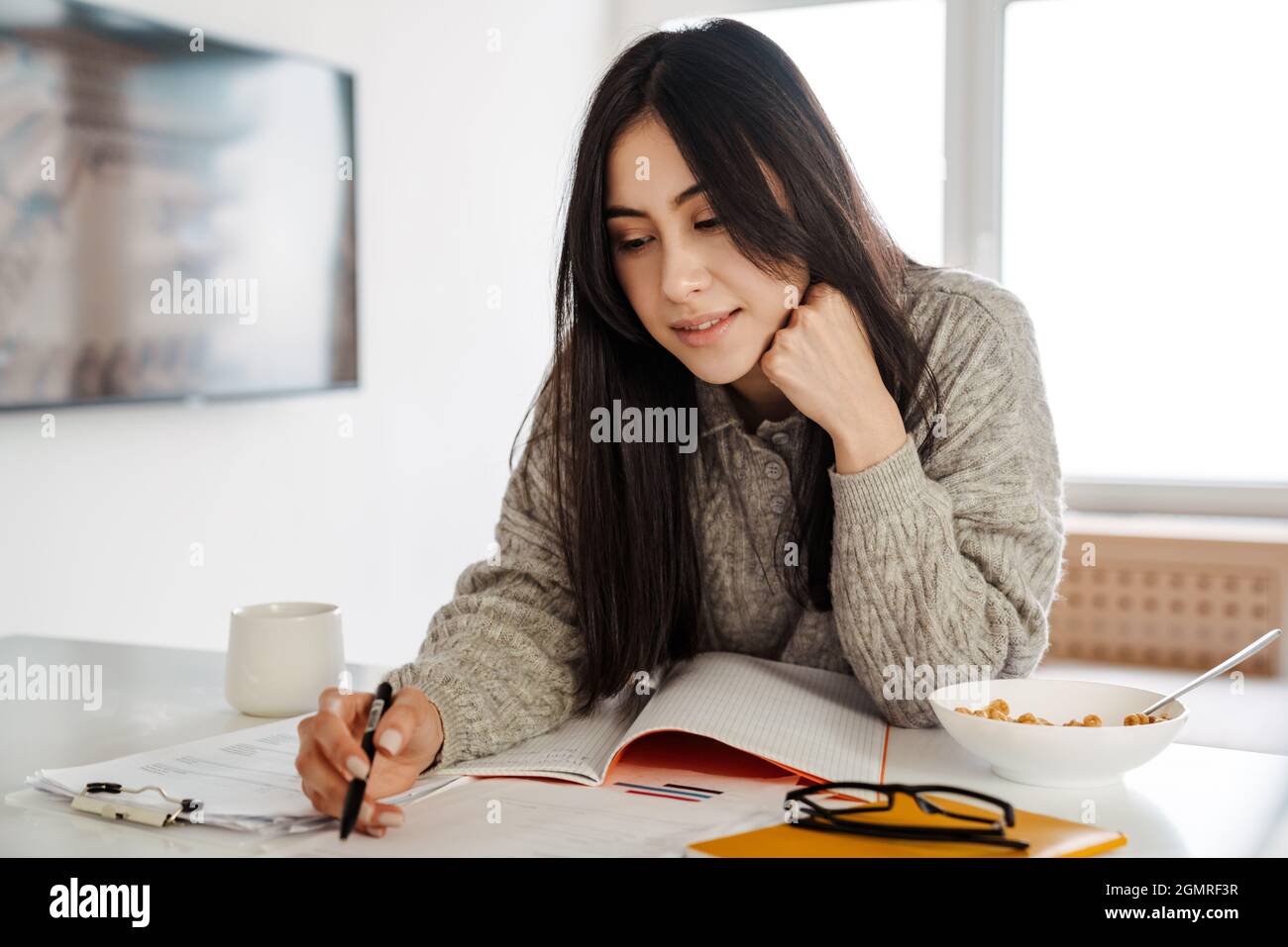 Attractive young smart woman studying while having healthy breakfast in ...