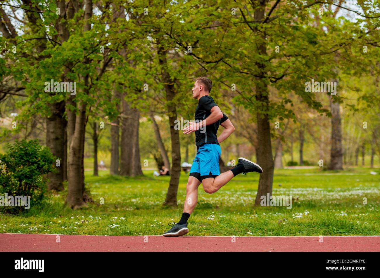 Handsome young man running on stadium track in stylish sportswear on ...