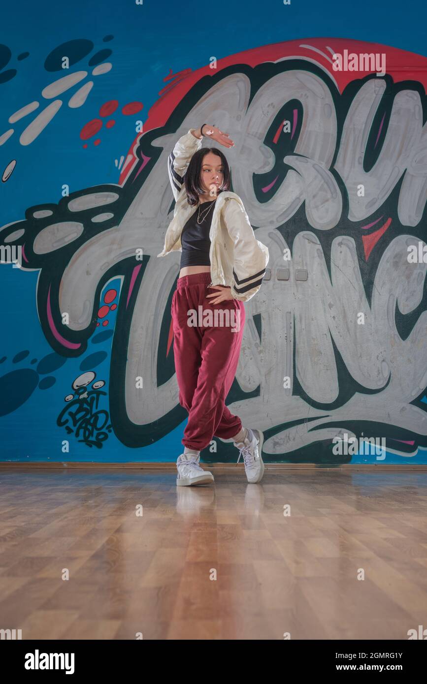 Attractive young woman doing breakdance move over graffiti background ...