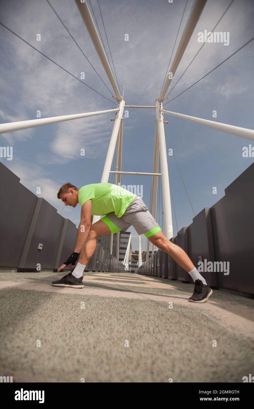 Strong sportsman is stretiching his legs on the bridge Stock Photo - Alamy
