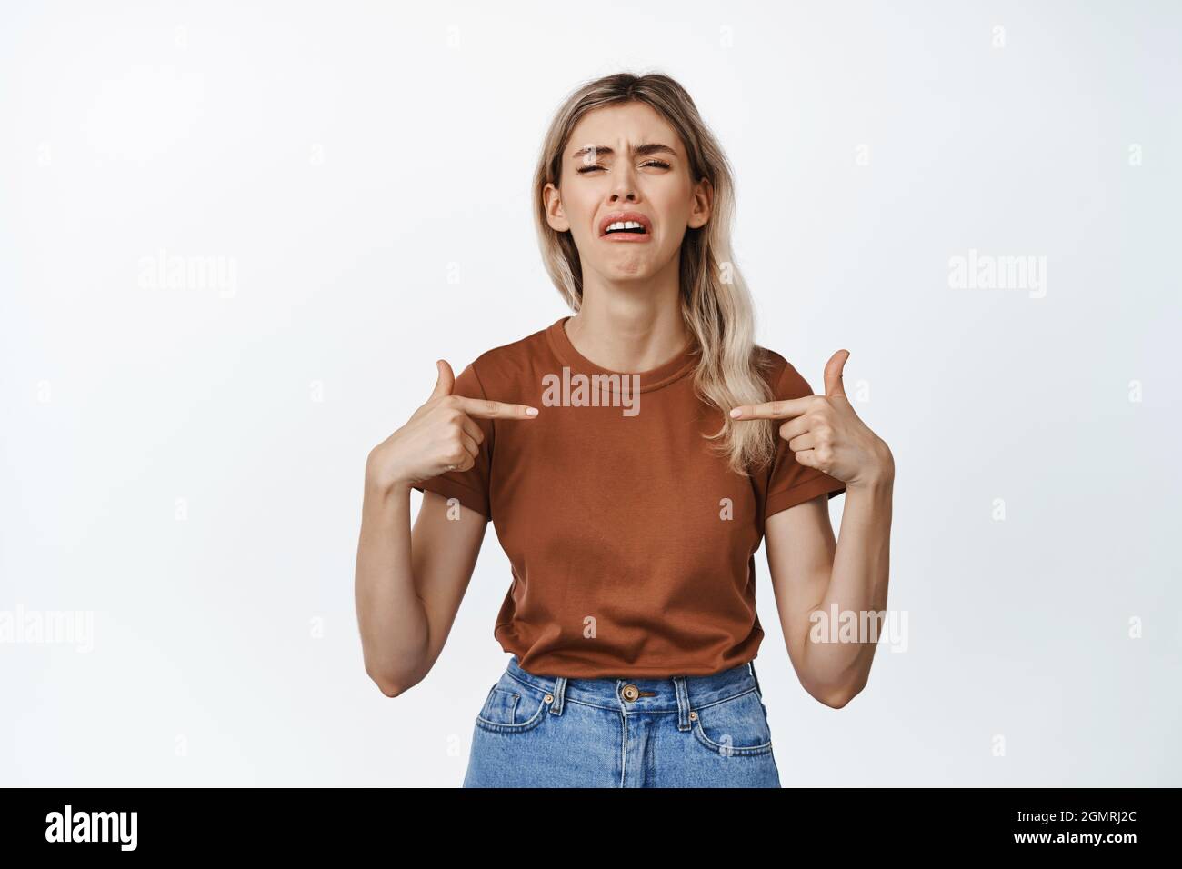 Sad and miserable girl pointing fingers at herself while crying ...