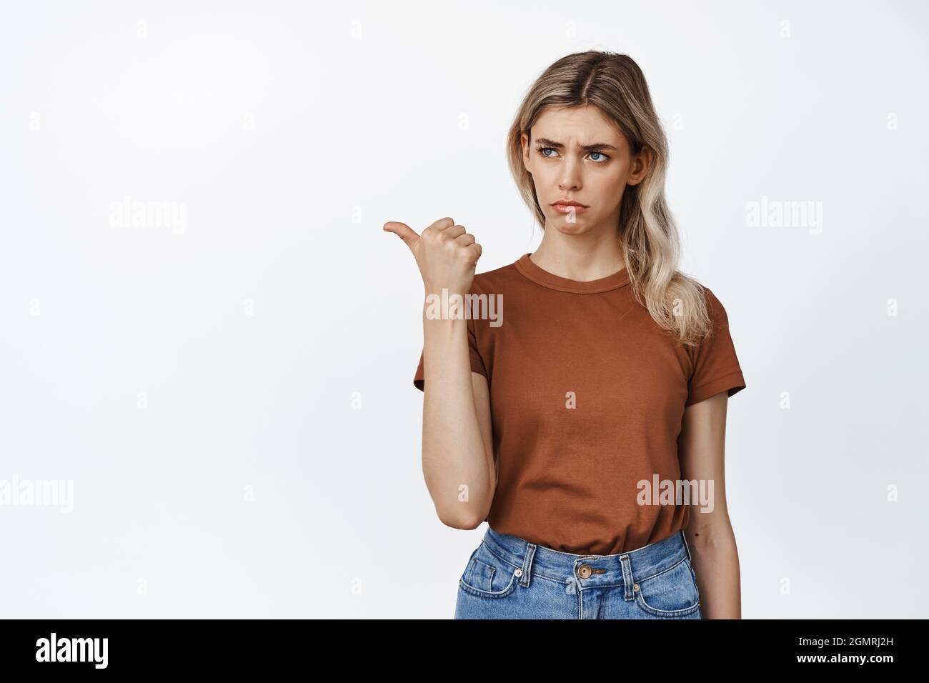 Portrait of blond girl frowning and looking at something sad, pointing ...
