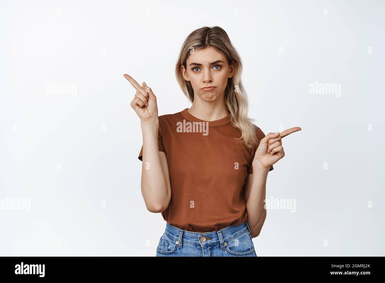 Image of sad young woman pointing fingers sideways at two lost options ...