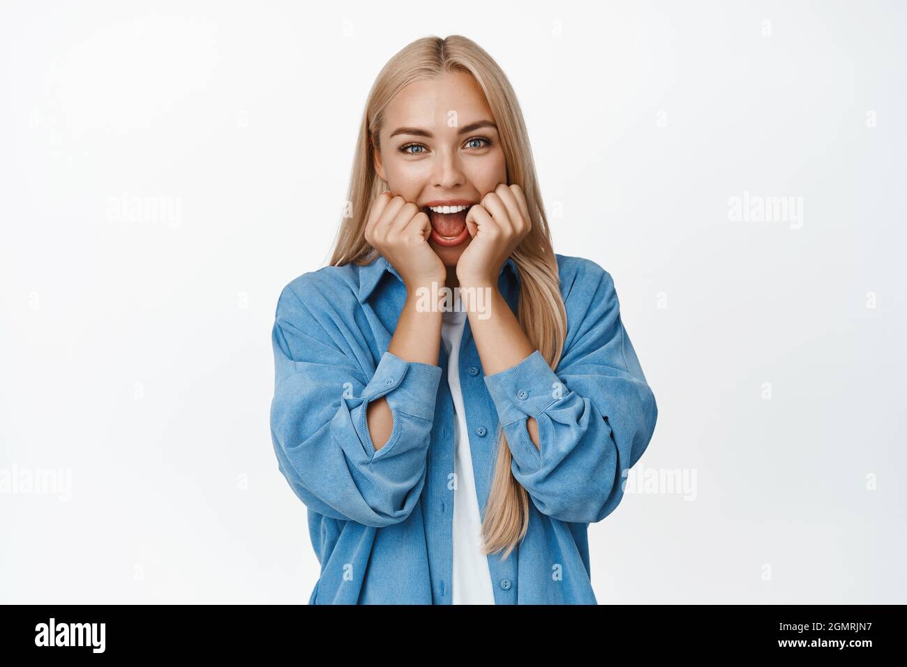 Cute and silly blond girl, squeeze her cheeks and smiling, looking ...