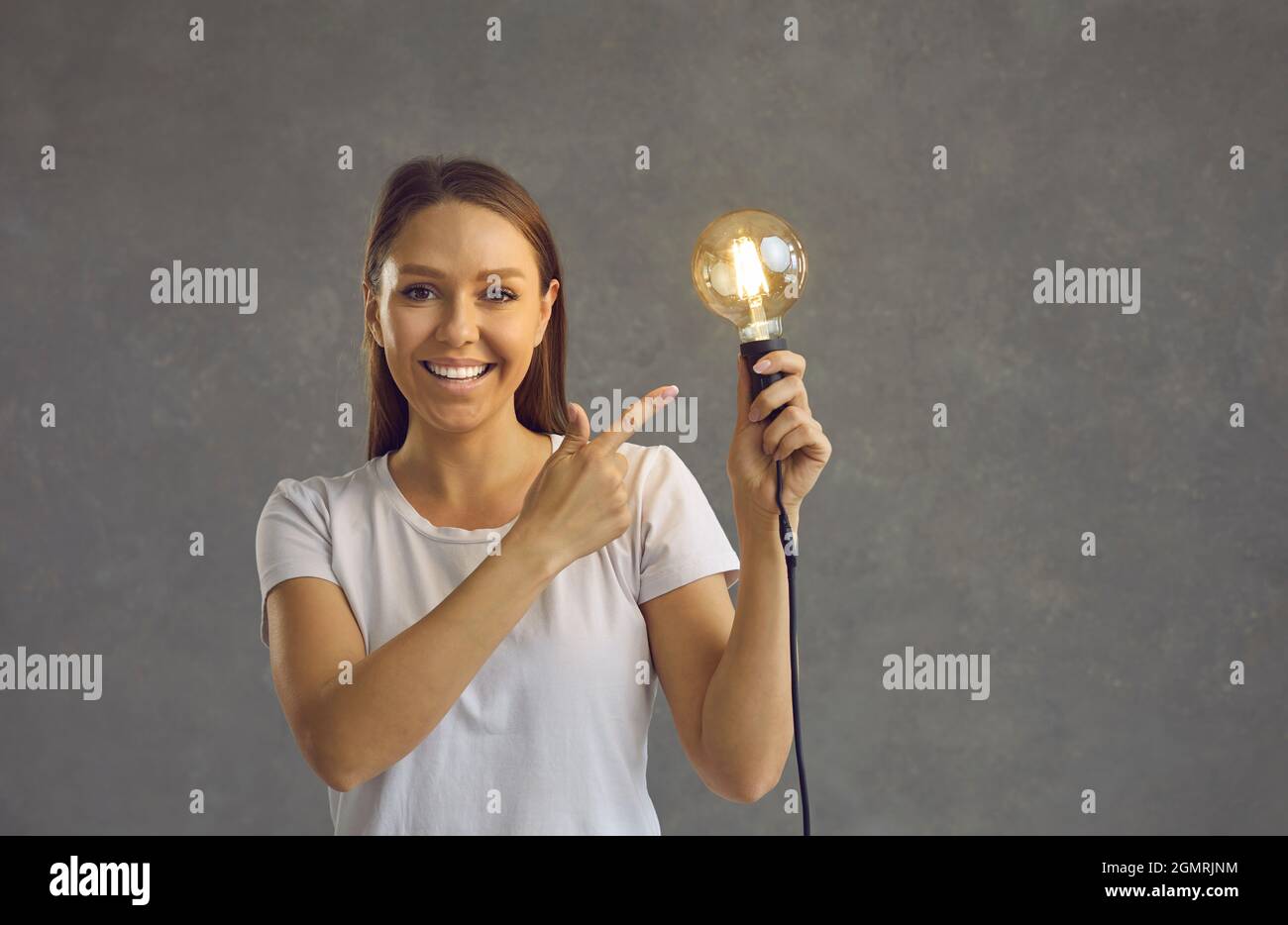 Happy beautiful woman holding light bulb suggesting good idea and smart ...