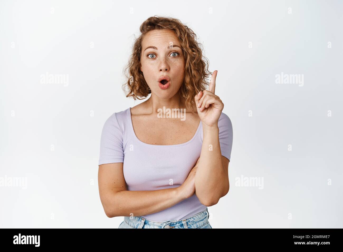 Portrait Of Amazed Blond Girl Pointing Finger Up Suggesting Something