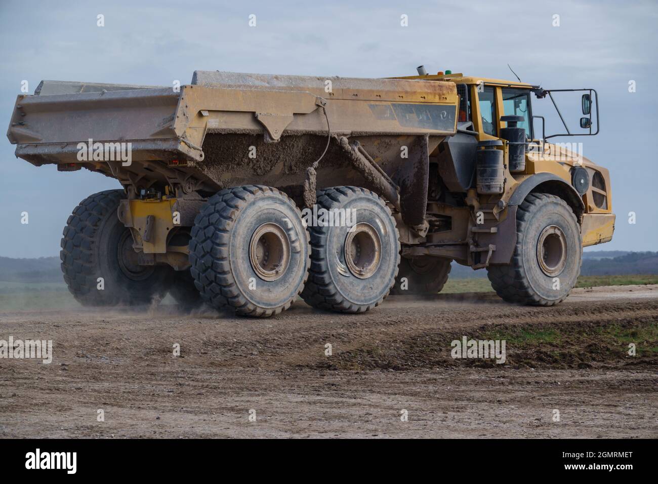 a yellow Volvo A40E articulated dump truck earth mover driving across ...