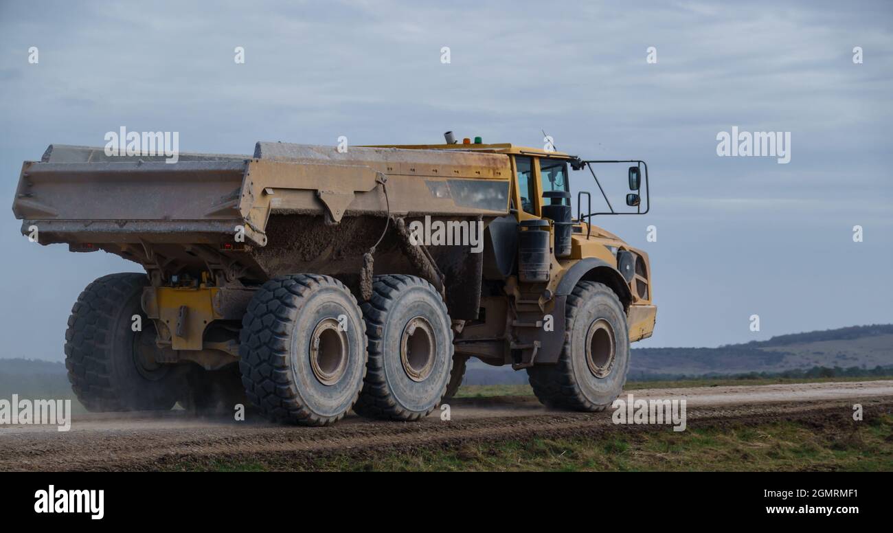 a yellow Volvo A40E articulated dump truck earth mover driving across ...