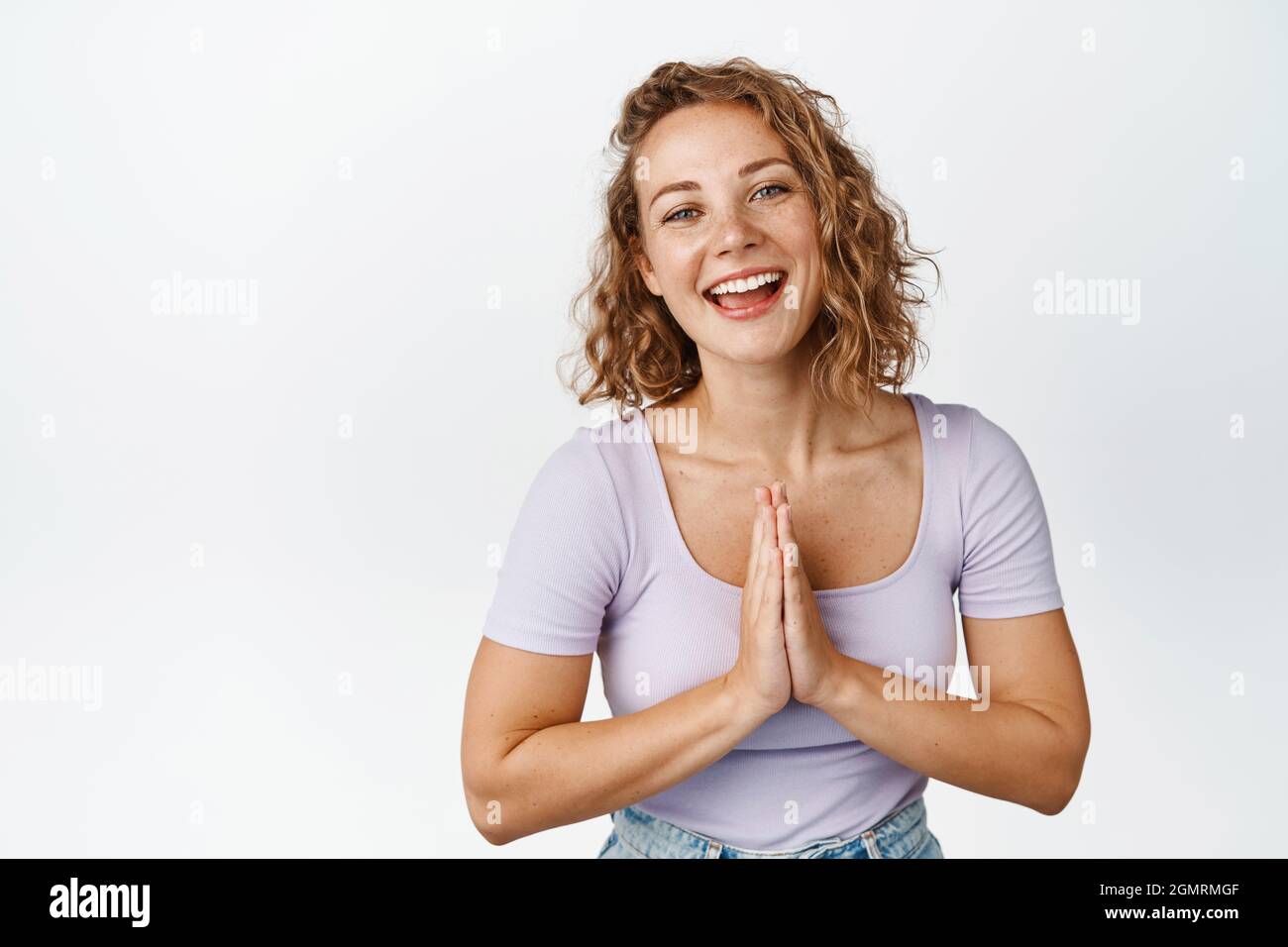 Cute blond girl saying thank you and bowing with namaste sign, smiling ...
