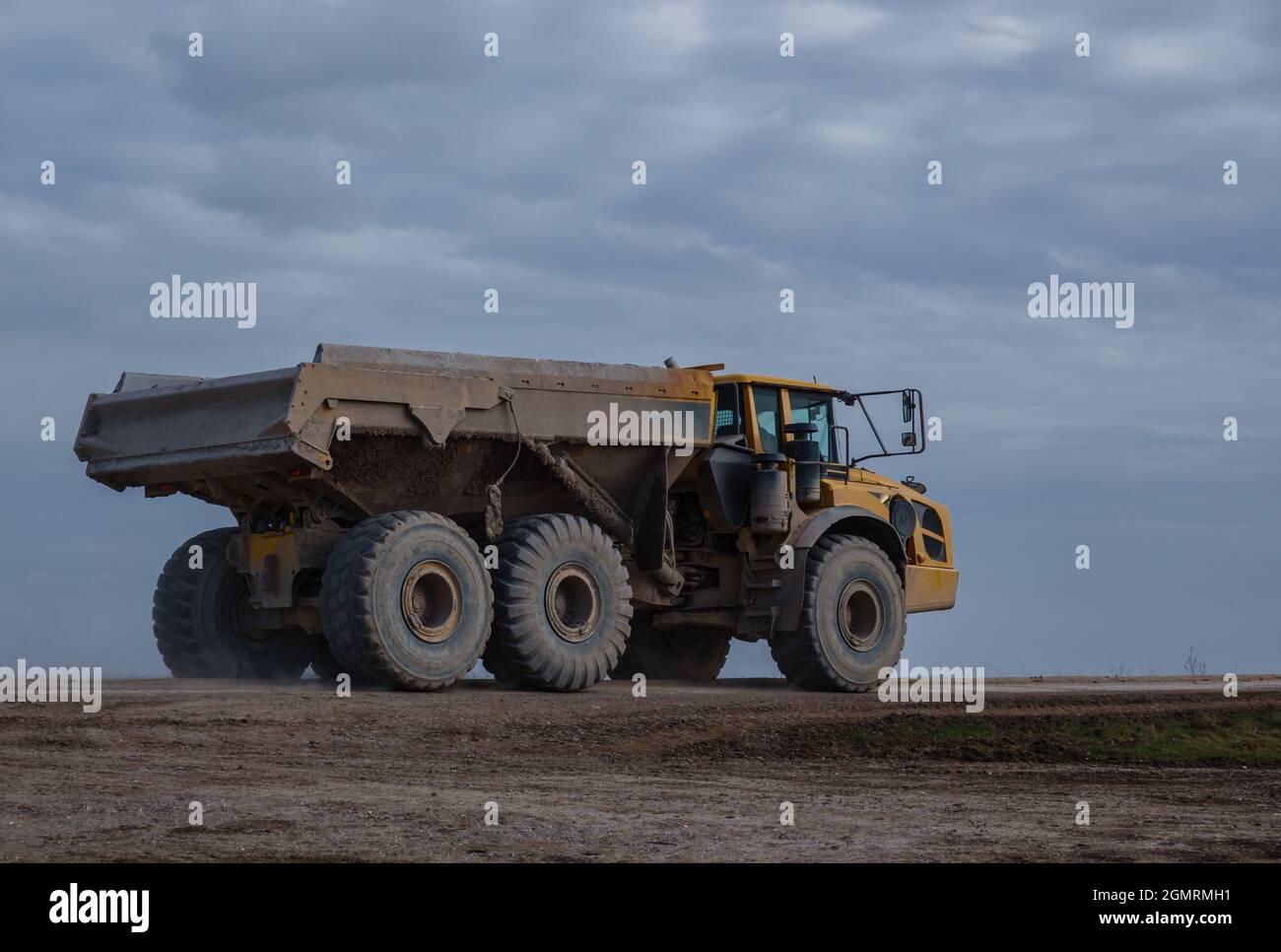 a yellow Volvo A40E articulated dump truck earth mover driving across ...