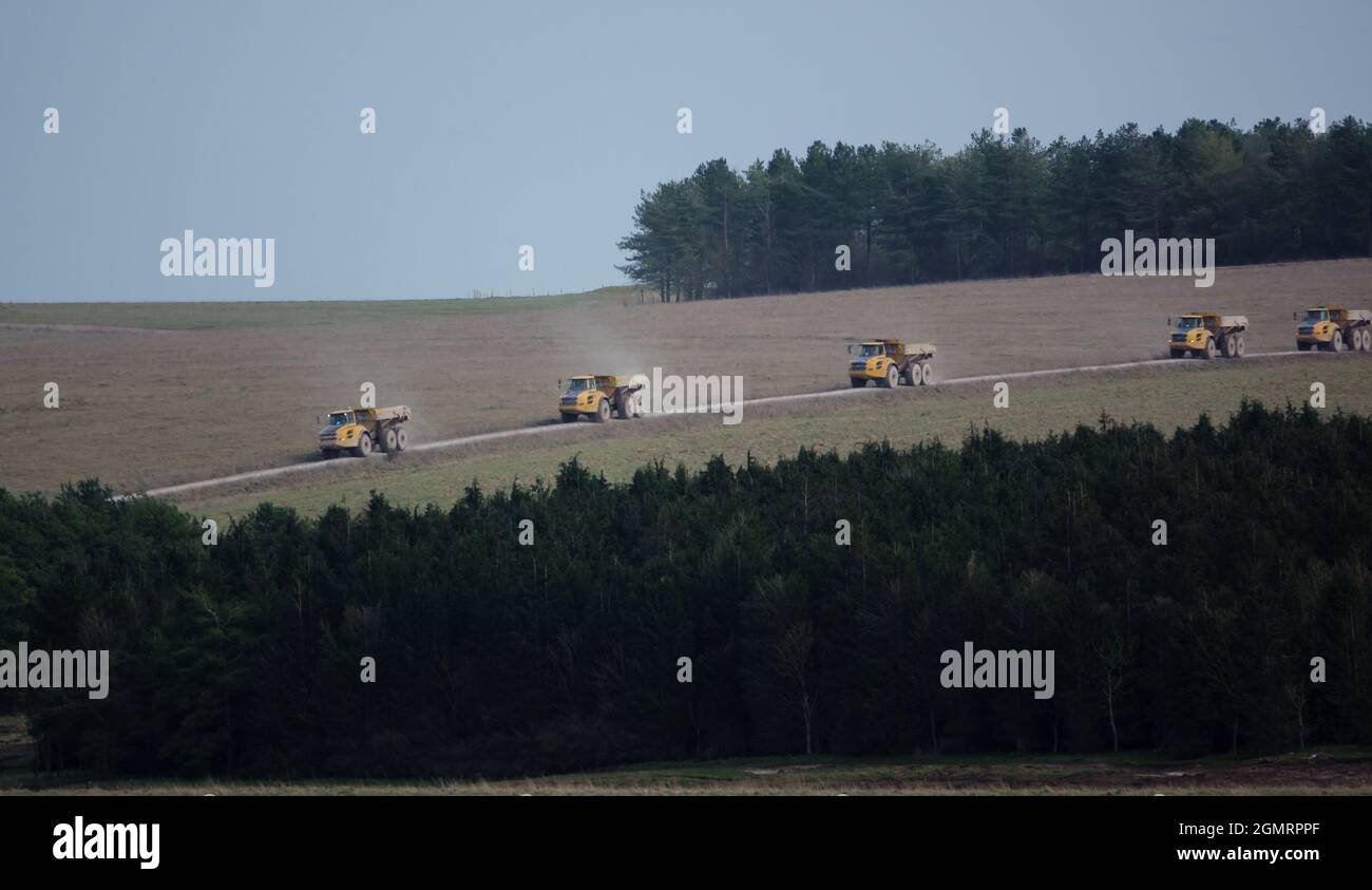 five yellow Volvo A40E articulated dump truck earth movers driving ...