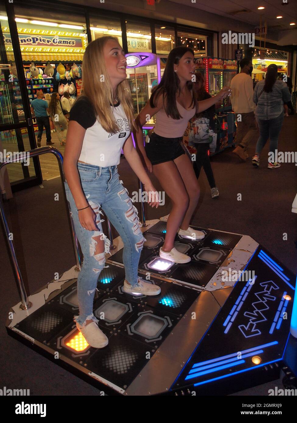 Two young female teens having fun at an arcade on the boardwalk in ...