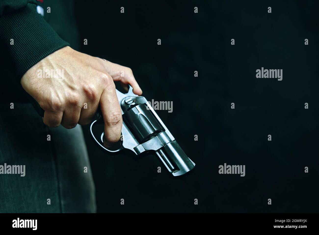 Firearm in man's hand. Criminal with revolver on dark background ...