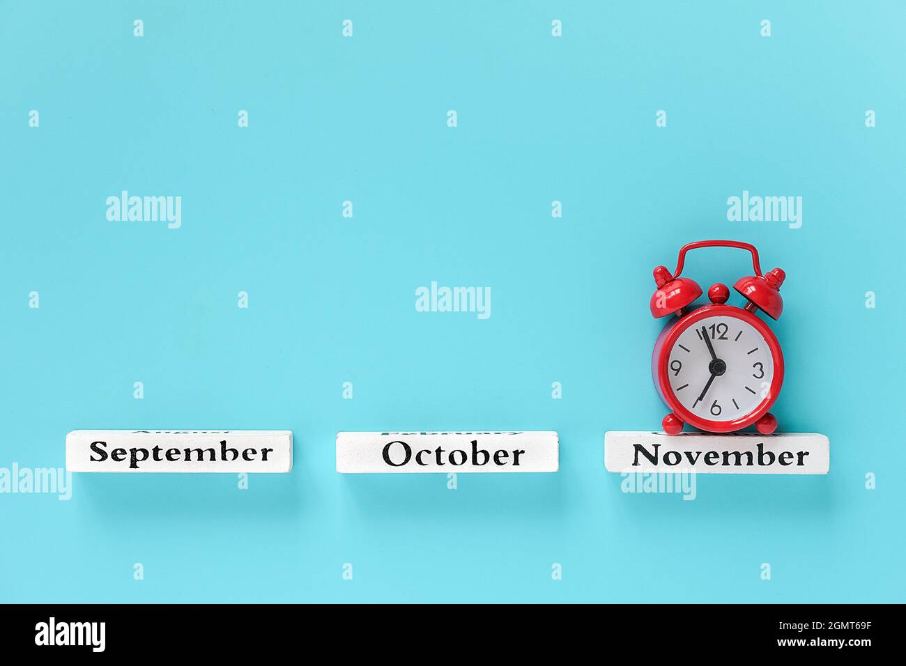 Wooden calendar autumn months and red alarm clock over November on blue ...