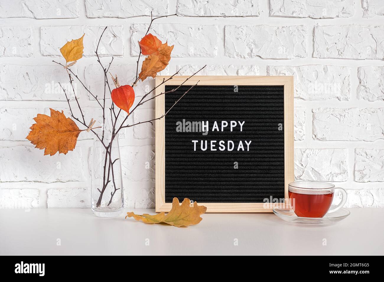 Happy Tuesday text on black letter board and bouquet of branches with ...