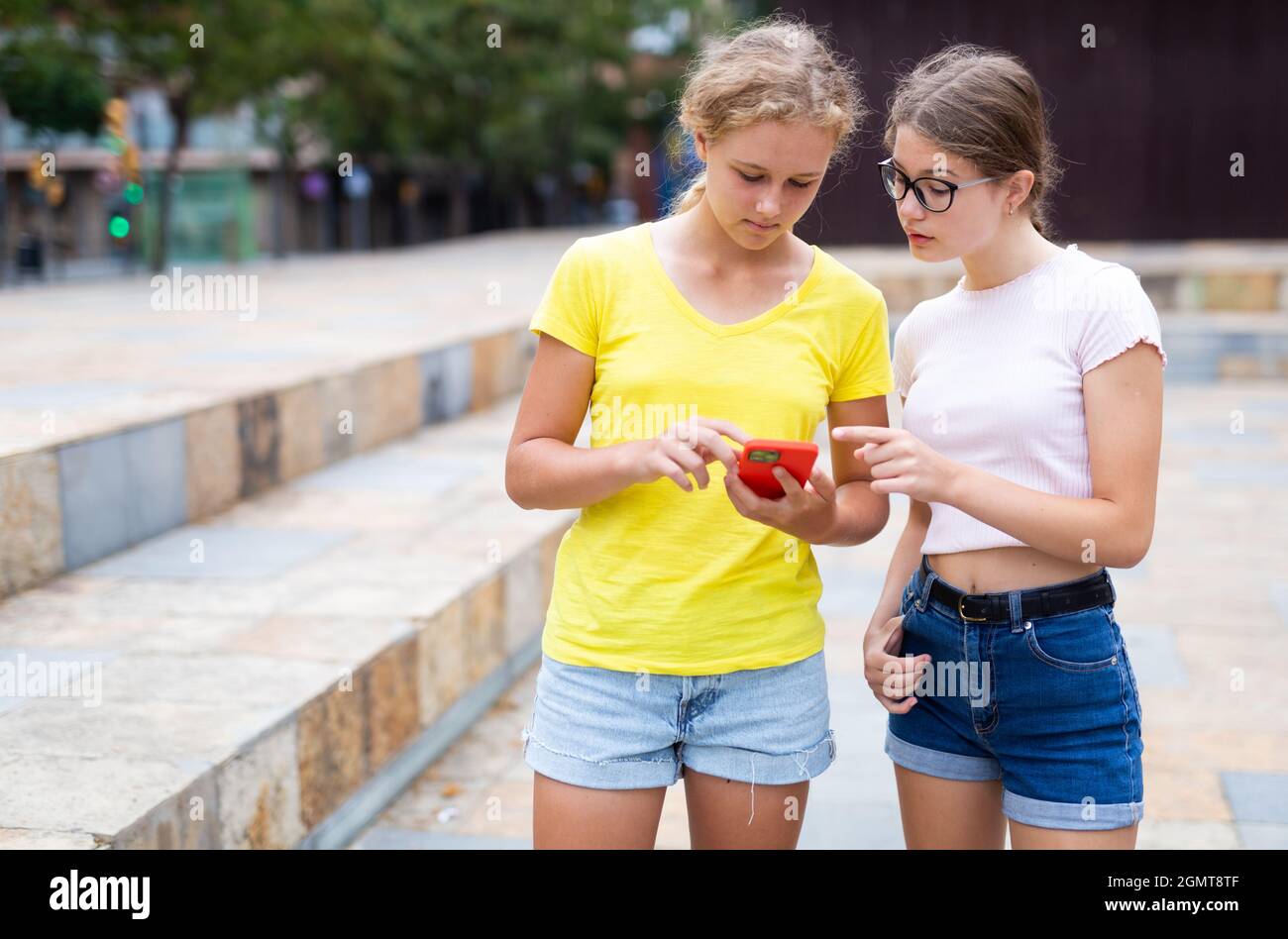 Two teenagers chatting on their smartphone Stock Photo - Alamy