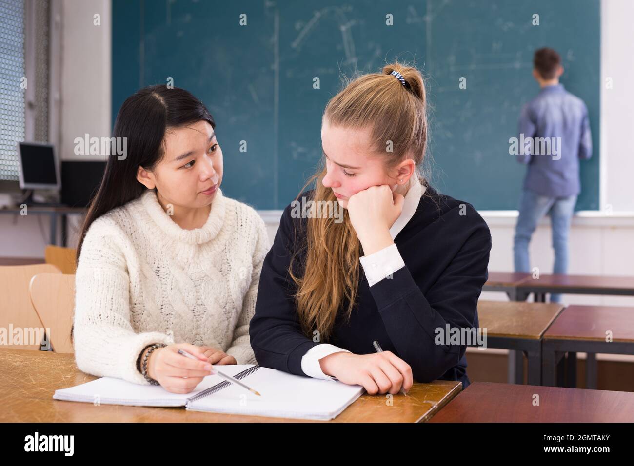 Asian teen girl explaining study material to female classmate Stock ...