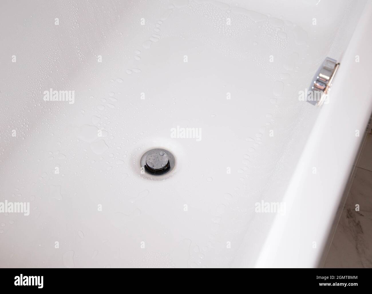 Modern silver drain plug in a new bathroom, water droplets on the walls ...