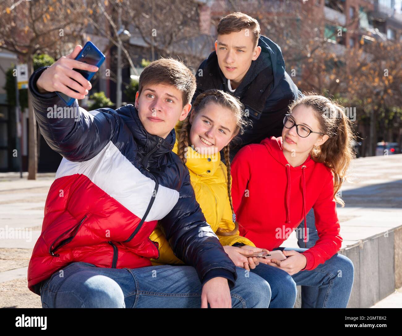 Four young happy teenagers taking self picture using mobile phone ...