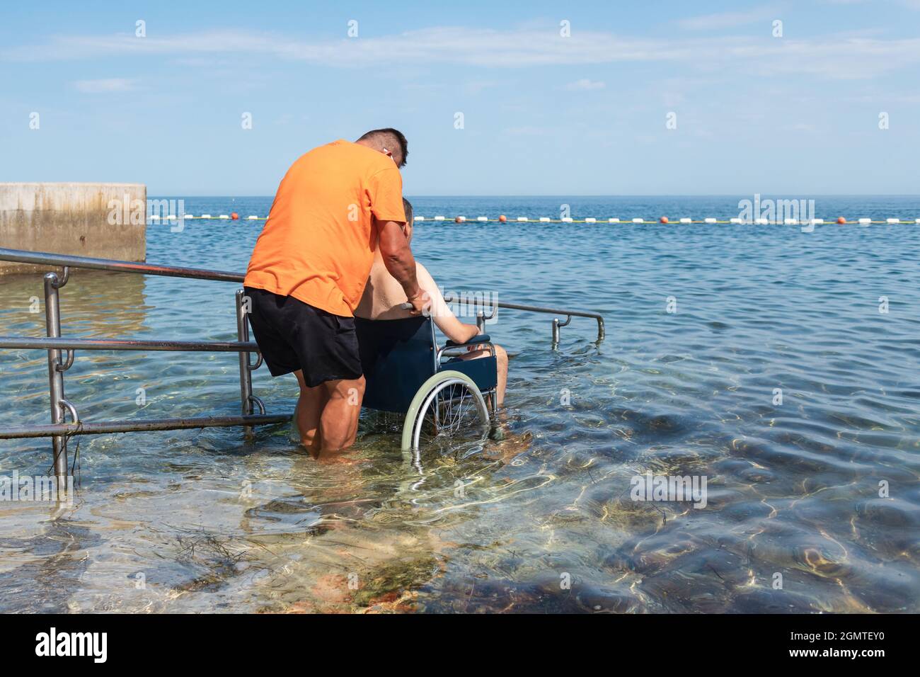 Wheelchair pushed down the ramp to the sea to enable disabled person ...