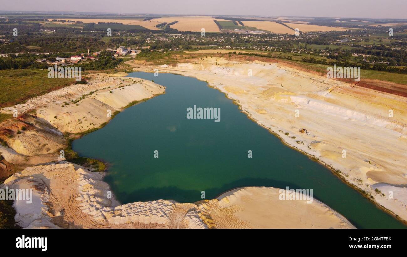 Sand quarry. Turquoise lagoon and surface mine with exposed colored ...
