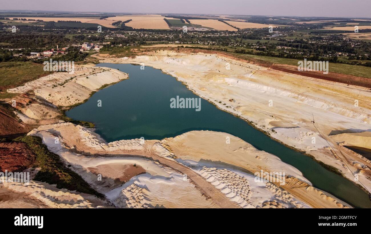 Sand quarry. Turquoise lagoon and surface mine with exposed colored ...