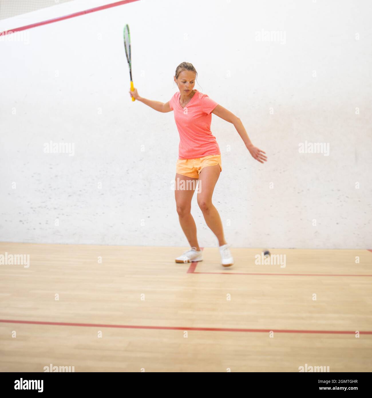 Pretty, female squash player on a squash court (motion blurred image ...