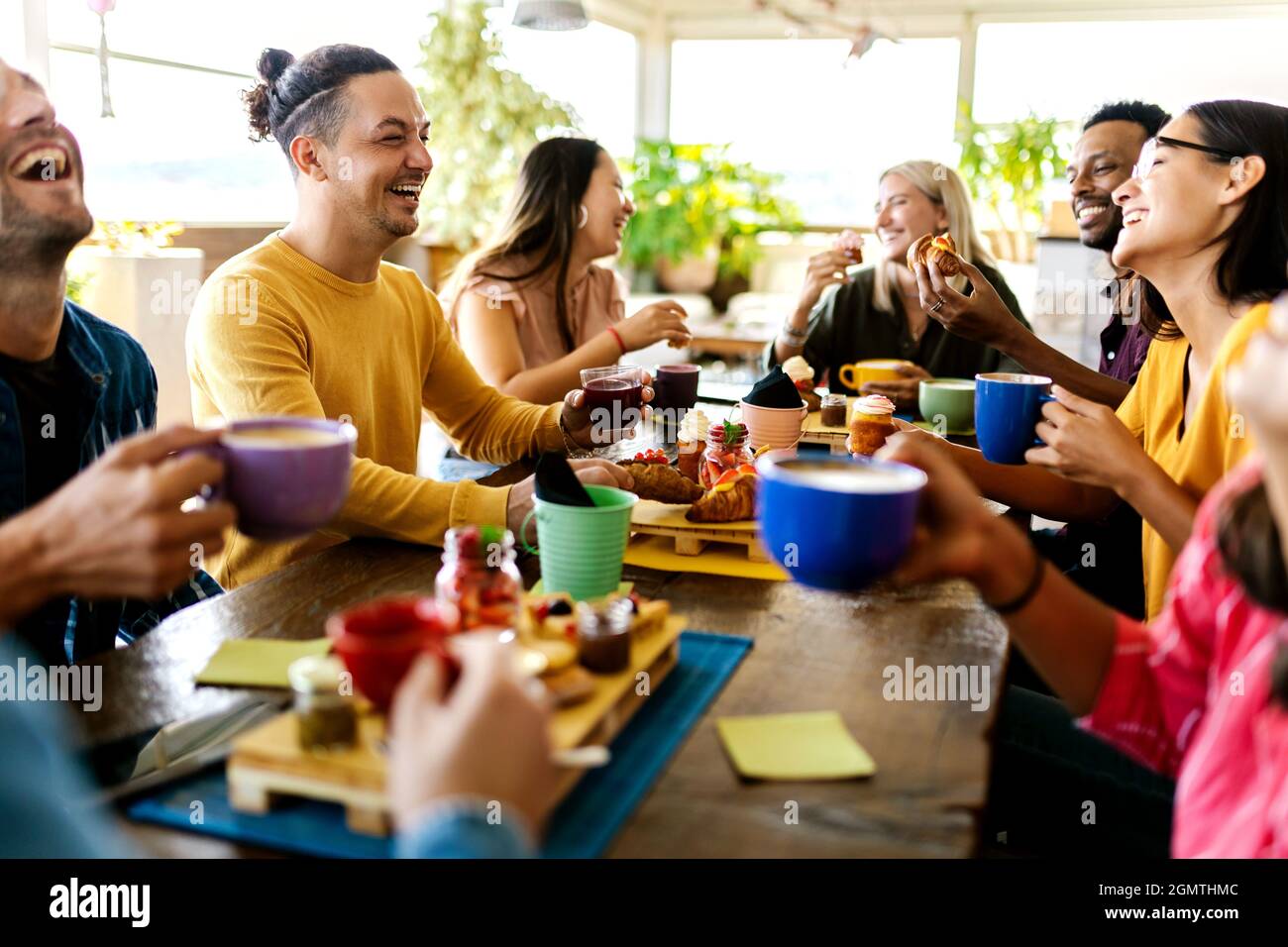 Smiling group of diverse friends having breakfast and talking at coffee ...