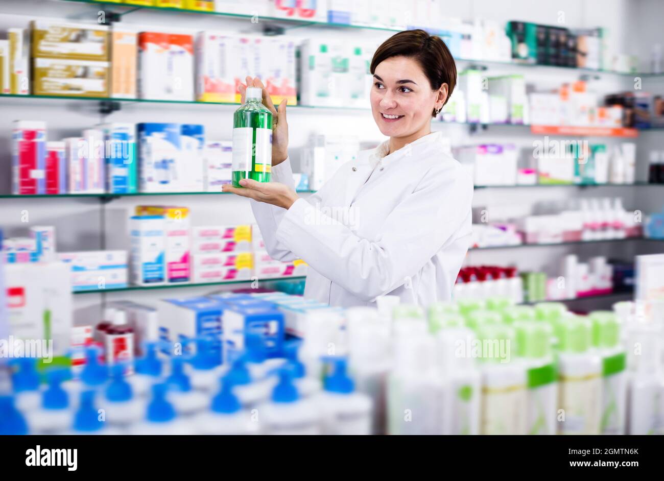 Happy female pharmacist offering products of body care in pharmacy ...