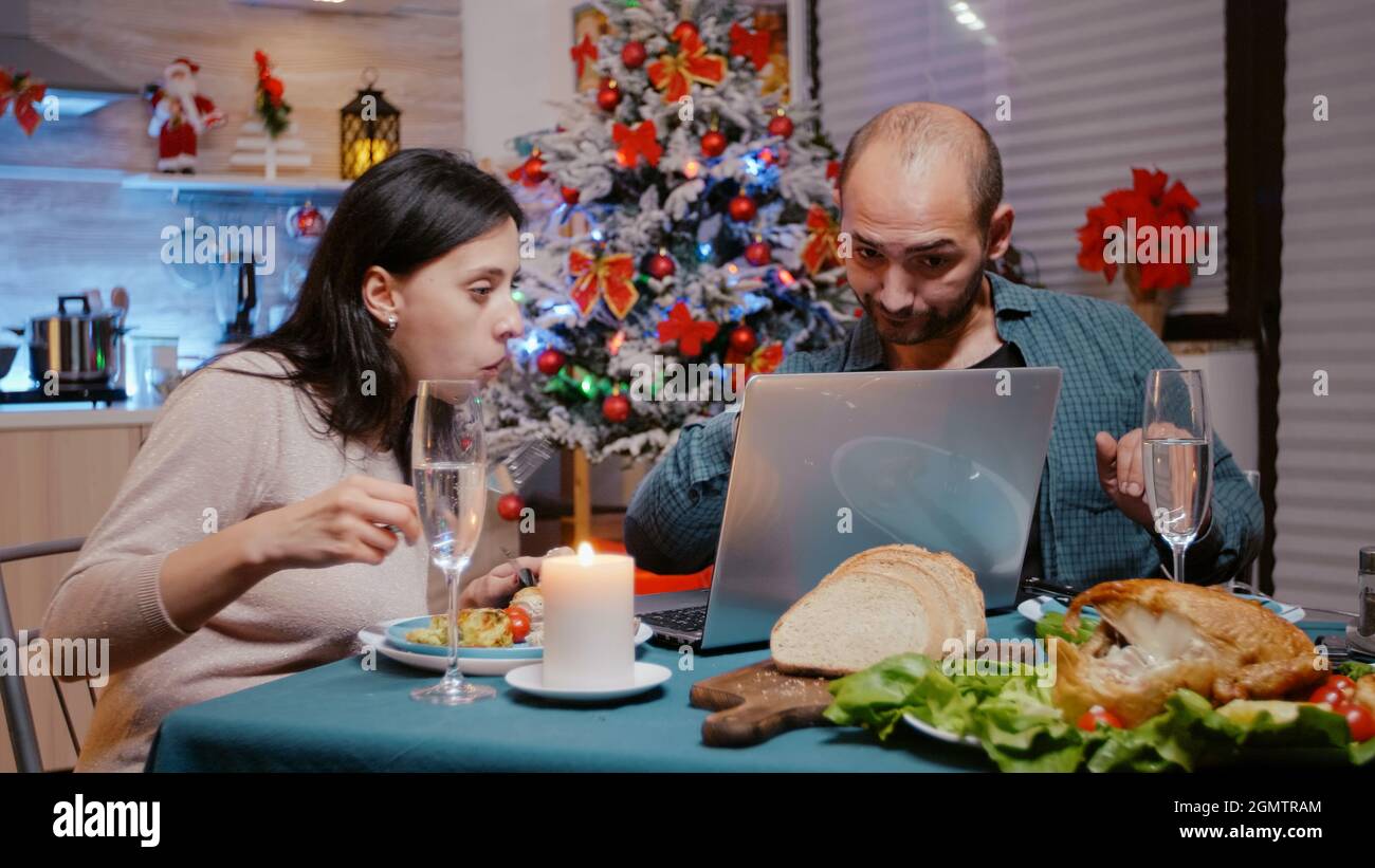 Couple looking laptop eating festive hi-res stock photography and ...