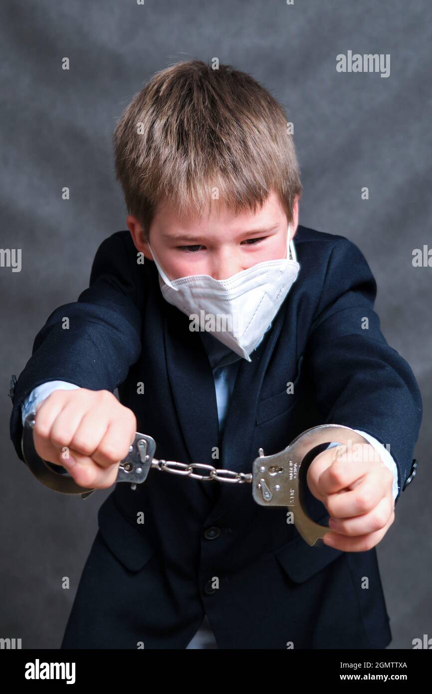 A boy in a medical mask on his face and in handcuffs, copy space on a ...