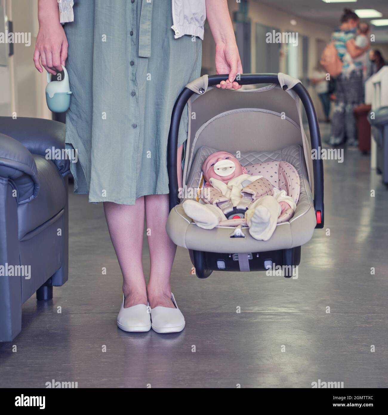 A mother with a newborn baby in a carrier is waiting for a doctor ...