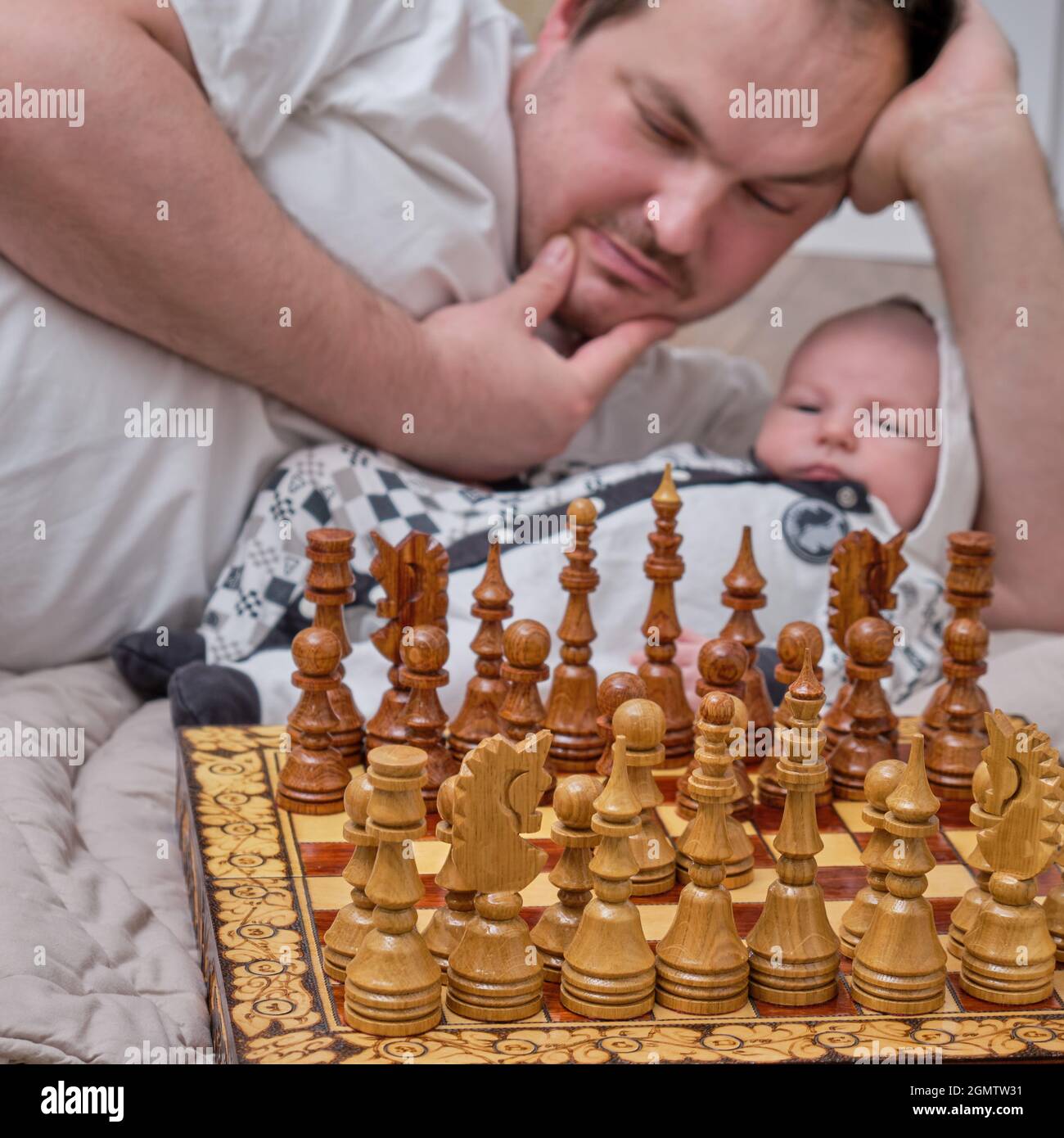 Man father and newborn baby boy near the chessboard with placed chess ...