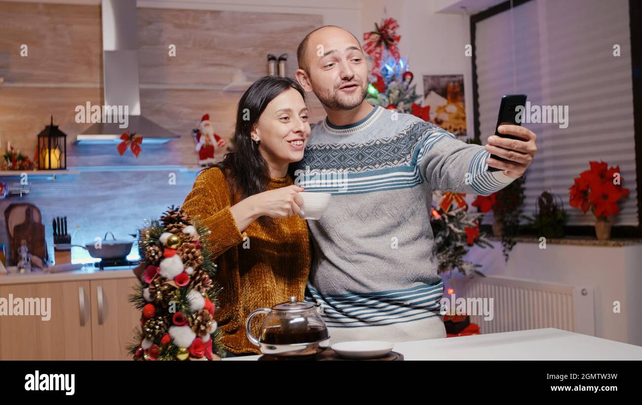 Festive couple talking to relatives on video call conference using ...