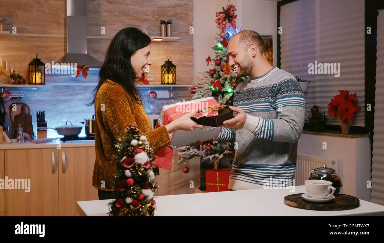 Couple exchanging presents for christmas eve festivity. Festive man and ...