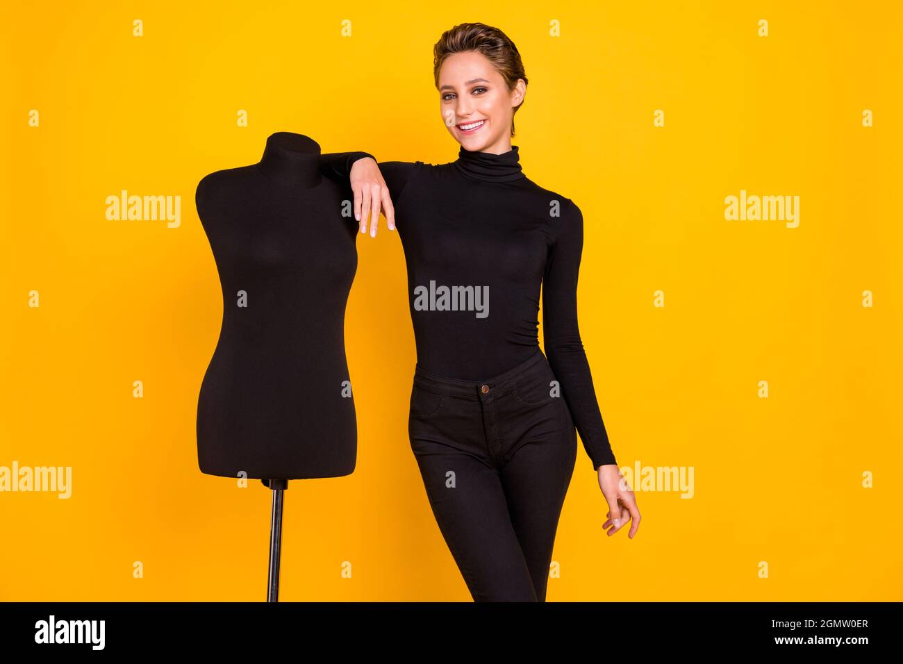 Portrait of attractive cheerful girl standing with dummy figure ...