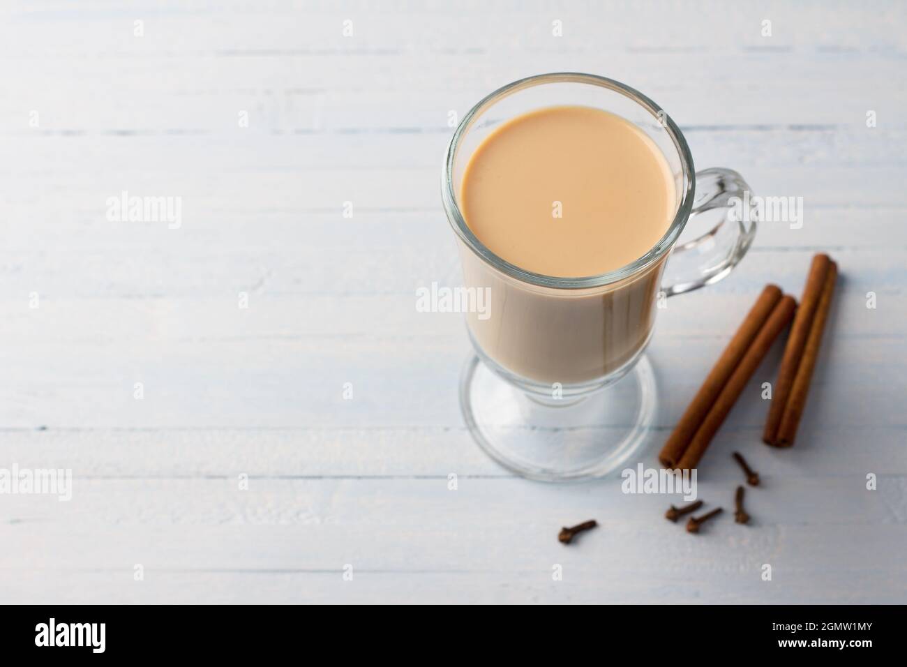 Spicy warming tea with milk in a glass cup with cinnamon sticks and ...