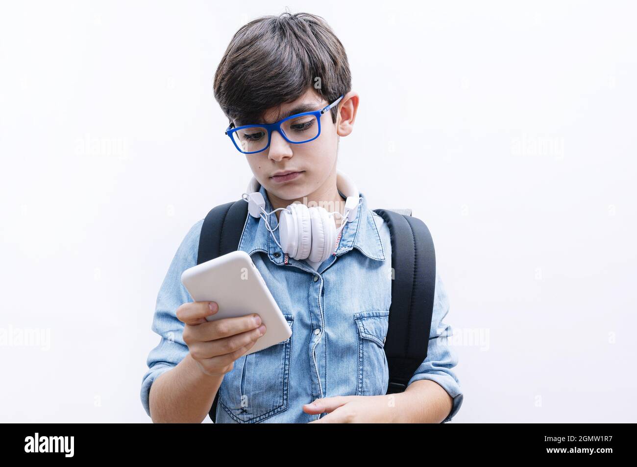 Caucasian teenage boy looking at his phone and ready for the new school ...