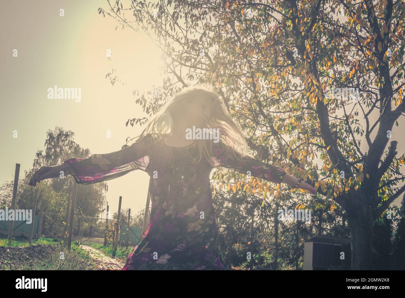 child in beautiful dress dancing wild in sunny backlit afternoon Stock ...