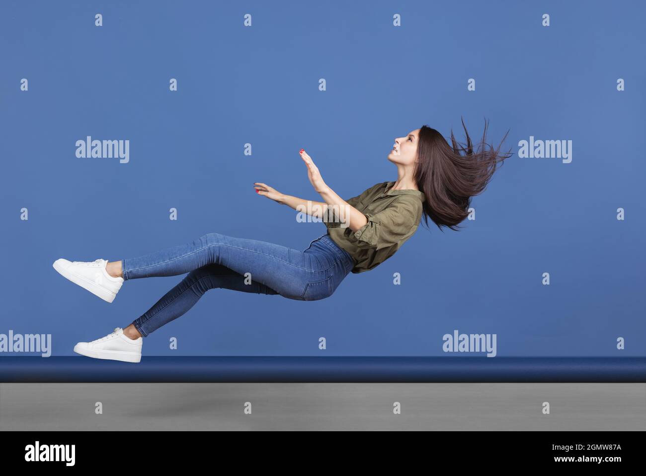 Full-length horizontal image of young girl falling isolated over blue ...