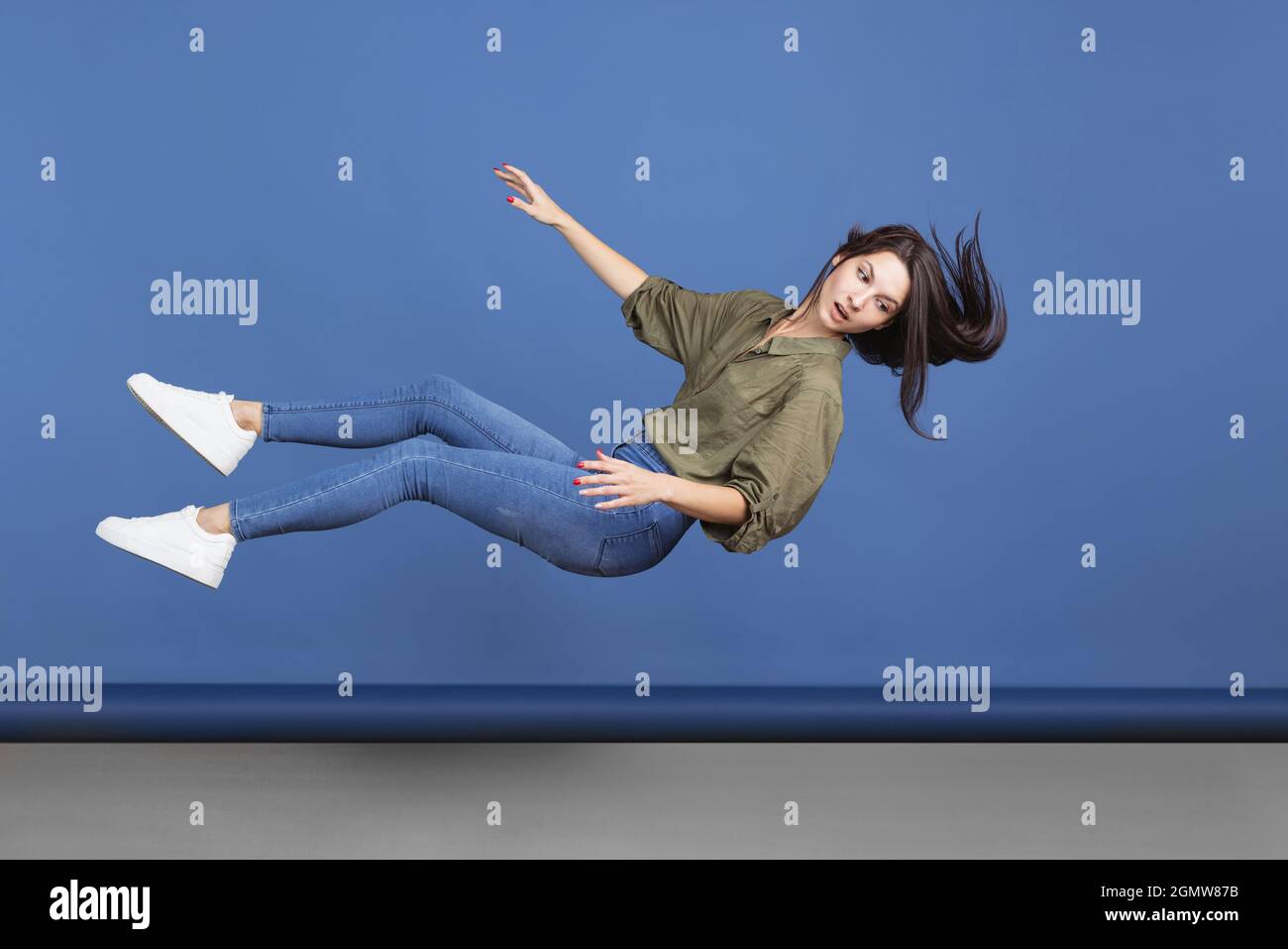 Full-length horizontal image of young girl falling isolated over blue ...