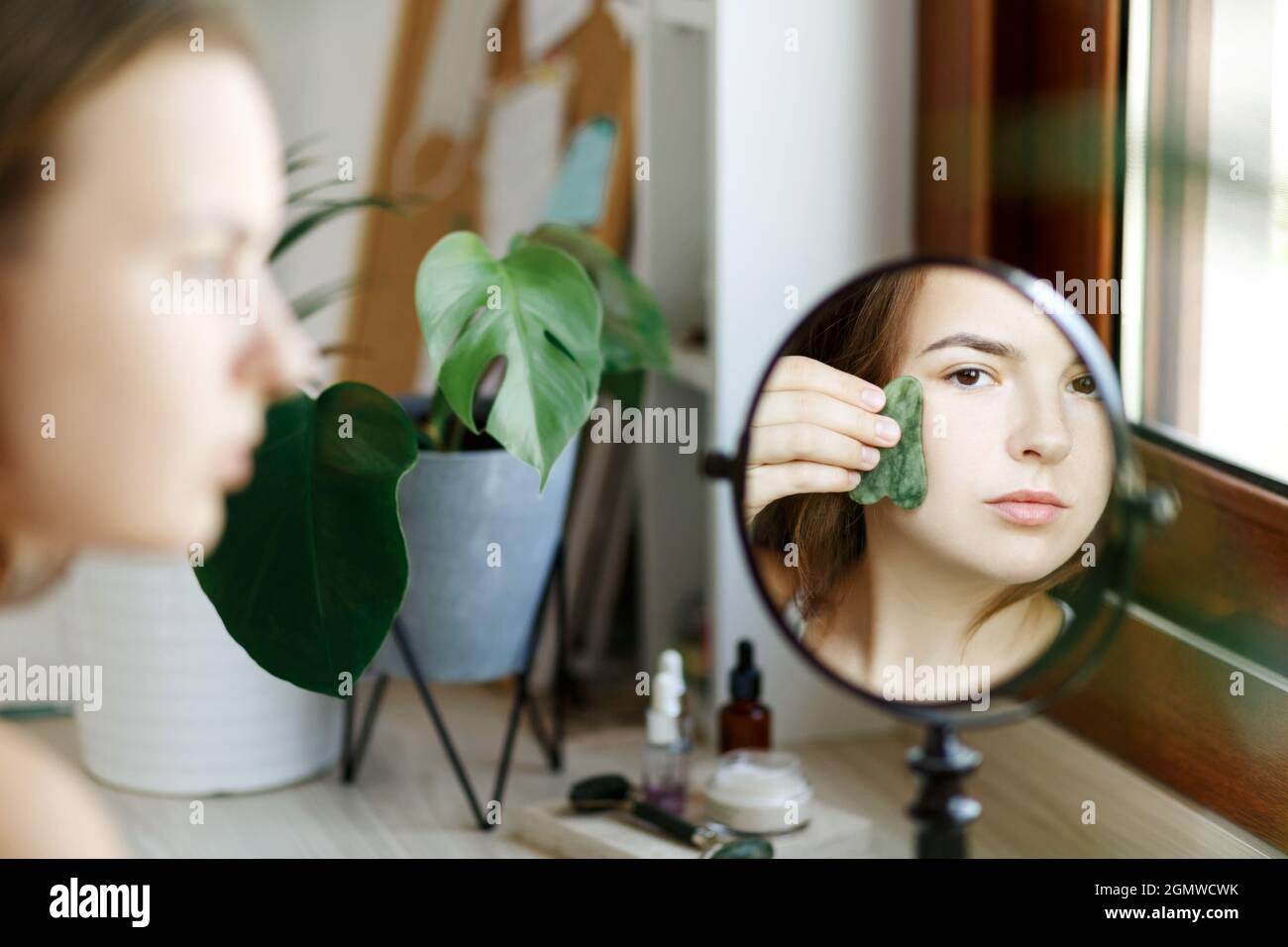 Close up portrait of adult caucasian woman,using natural gua sha jade ...