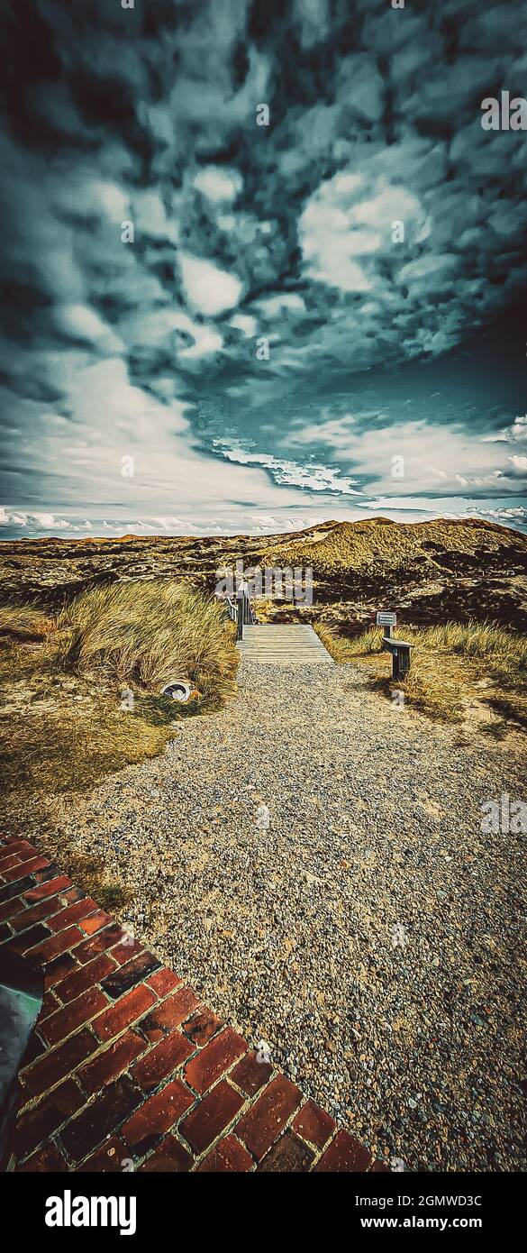 Scenic view of a grassy coast with a wooden boardwalk under a cloudy ...