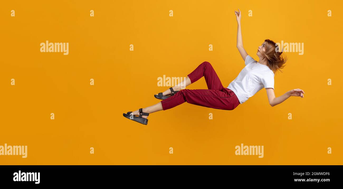Studio shot of young cute girl isolated falling down isolated on yellow ...