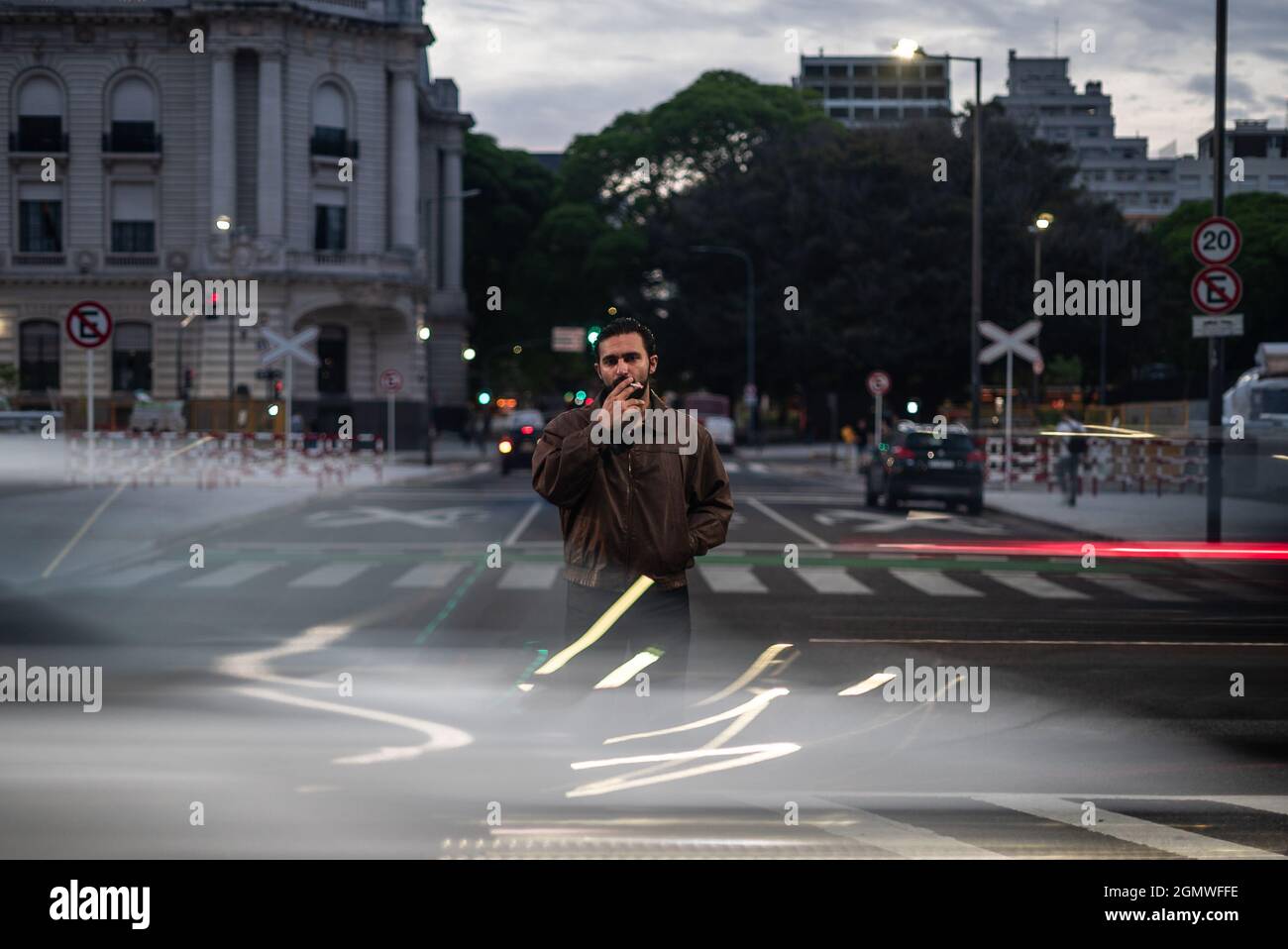 Hispanic man smoking a cigarette on a street with a timelapse of ...