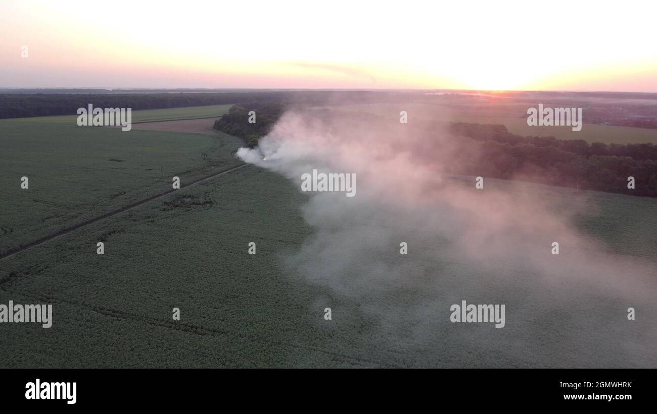 Fire at a landfill with garbage near agricultural fields. Smoke on a ...