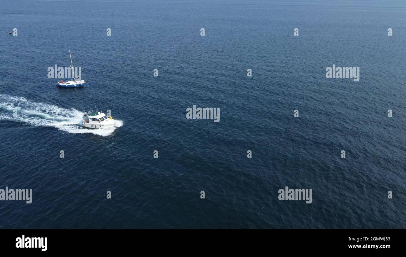 A white boat is racing at high speed on the waves of the blue sea. Rest ...