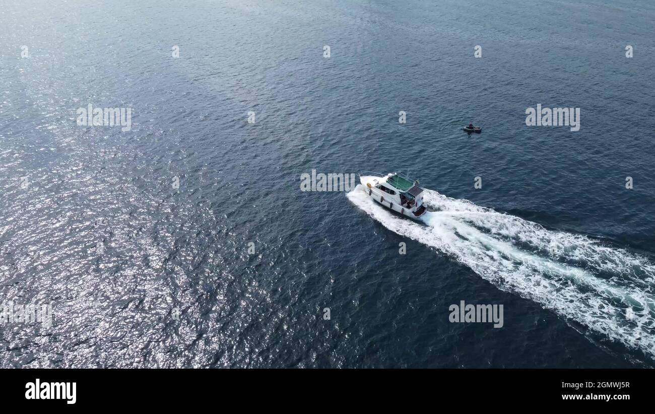 White big boat motion on blue water aerial view. Flight over a white ...