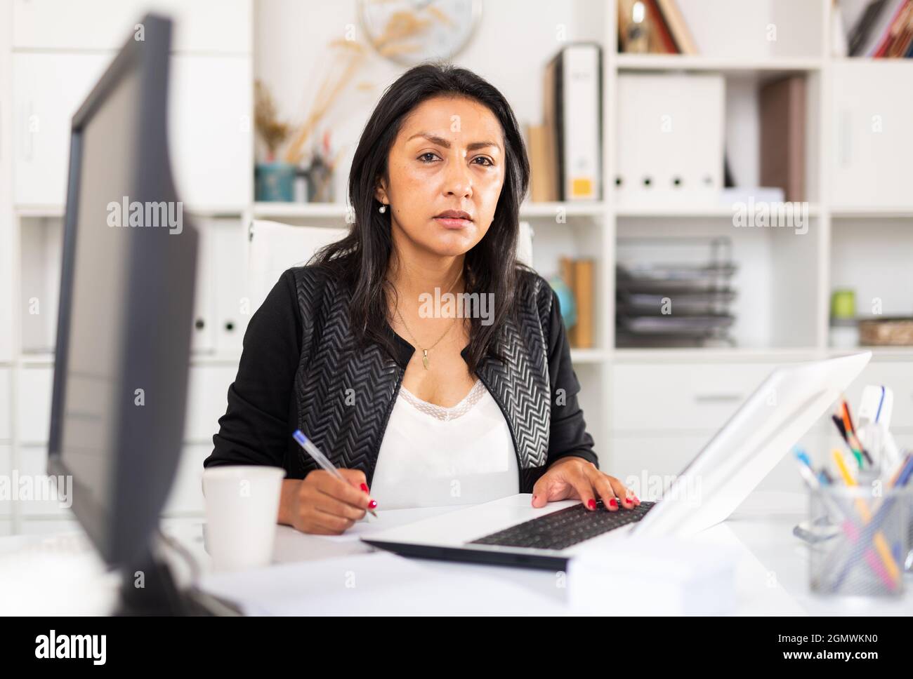 Portrait of confident latin american female office employee during ...